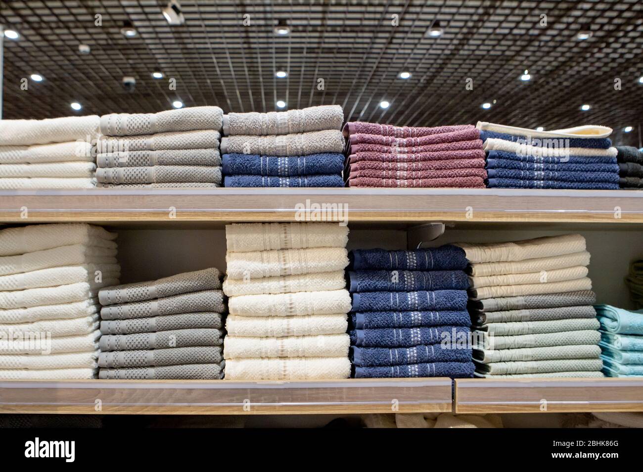 Folded multicolored towels on shelves. Neatly folded clothes. Rack of ...