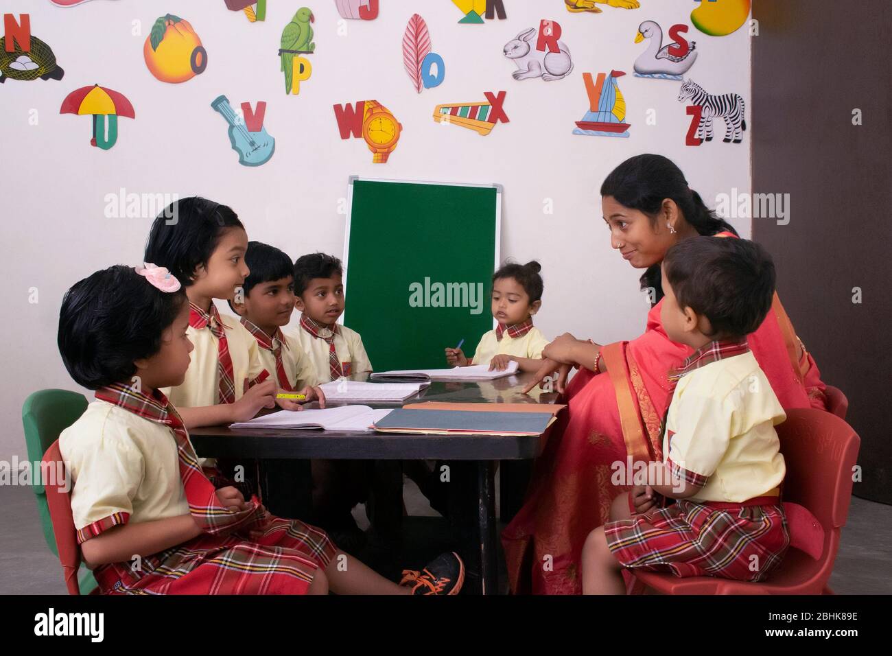 Teacher helping elementary school children in classroom Stock Photo - Alamy