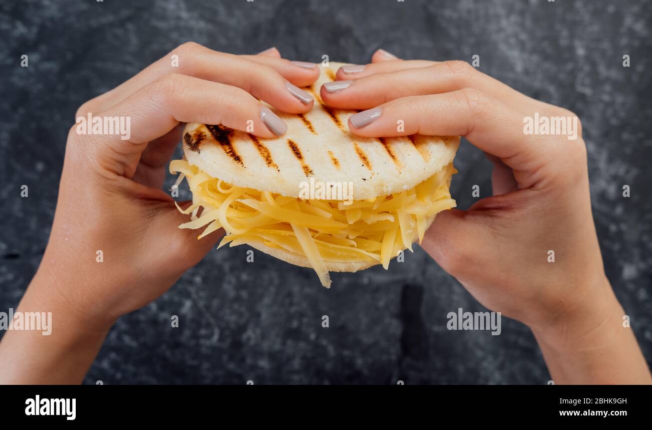 Woman holding a cheese arepa, typical of Venezuelan cuisine Stock Photo ...