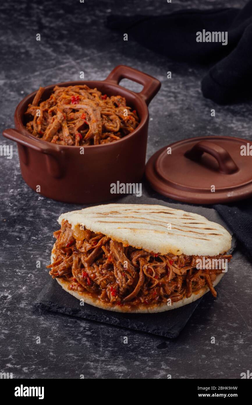 Arepa stuffed with shredded meat on a dark background. (Arepa con carne ...