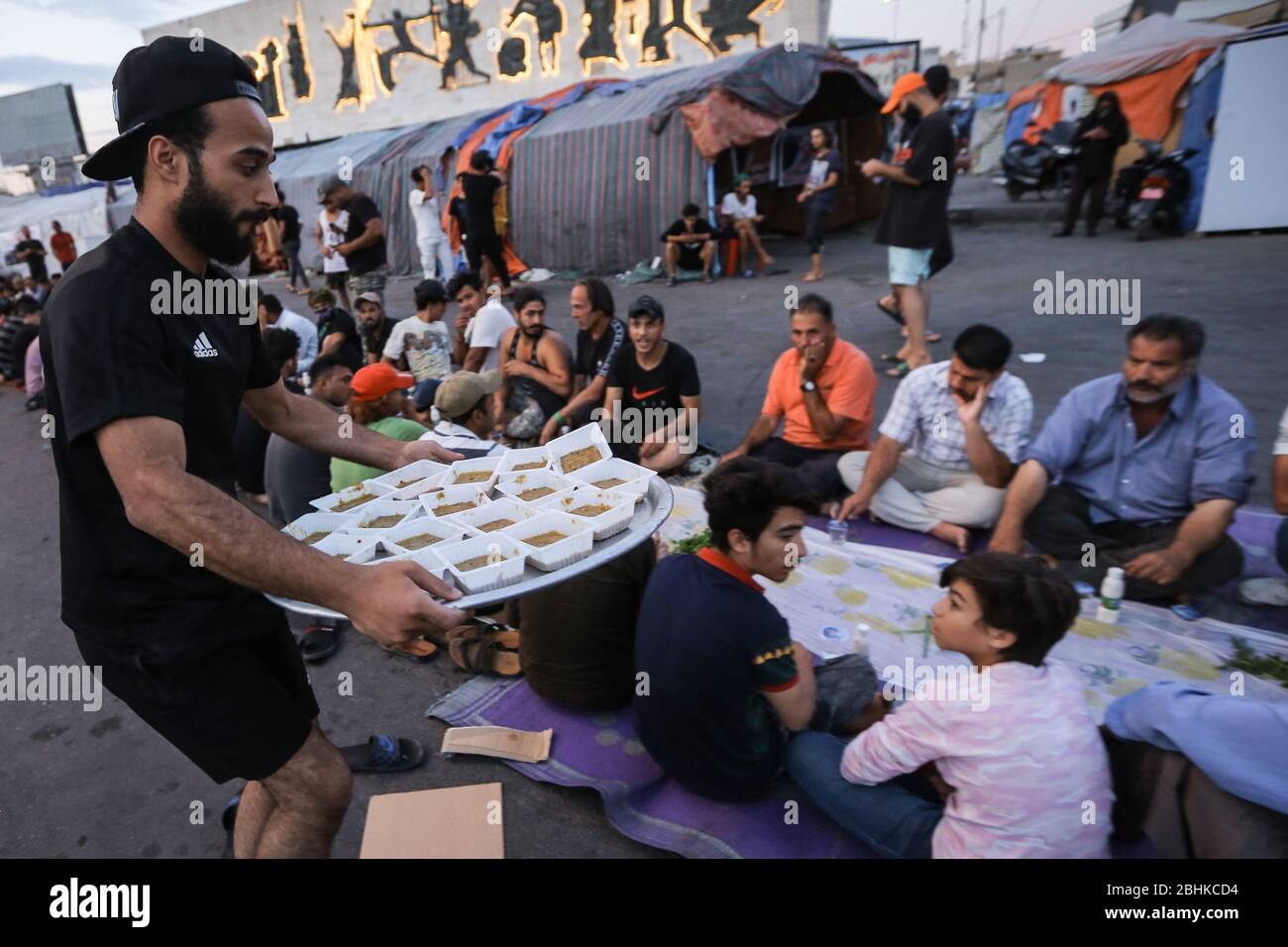Baghdad, Iraq. 26th Apr, 2020. A man distributes food for Iraqi ...