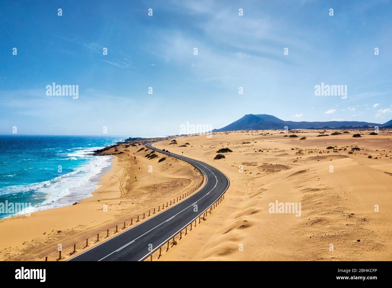 Rocky coastline and highway with golden sand and blue water, post ...
