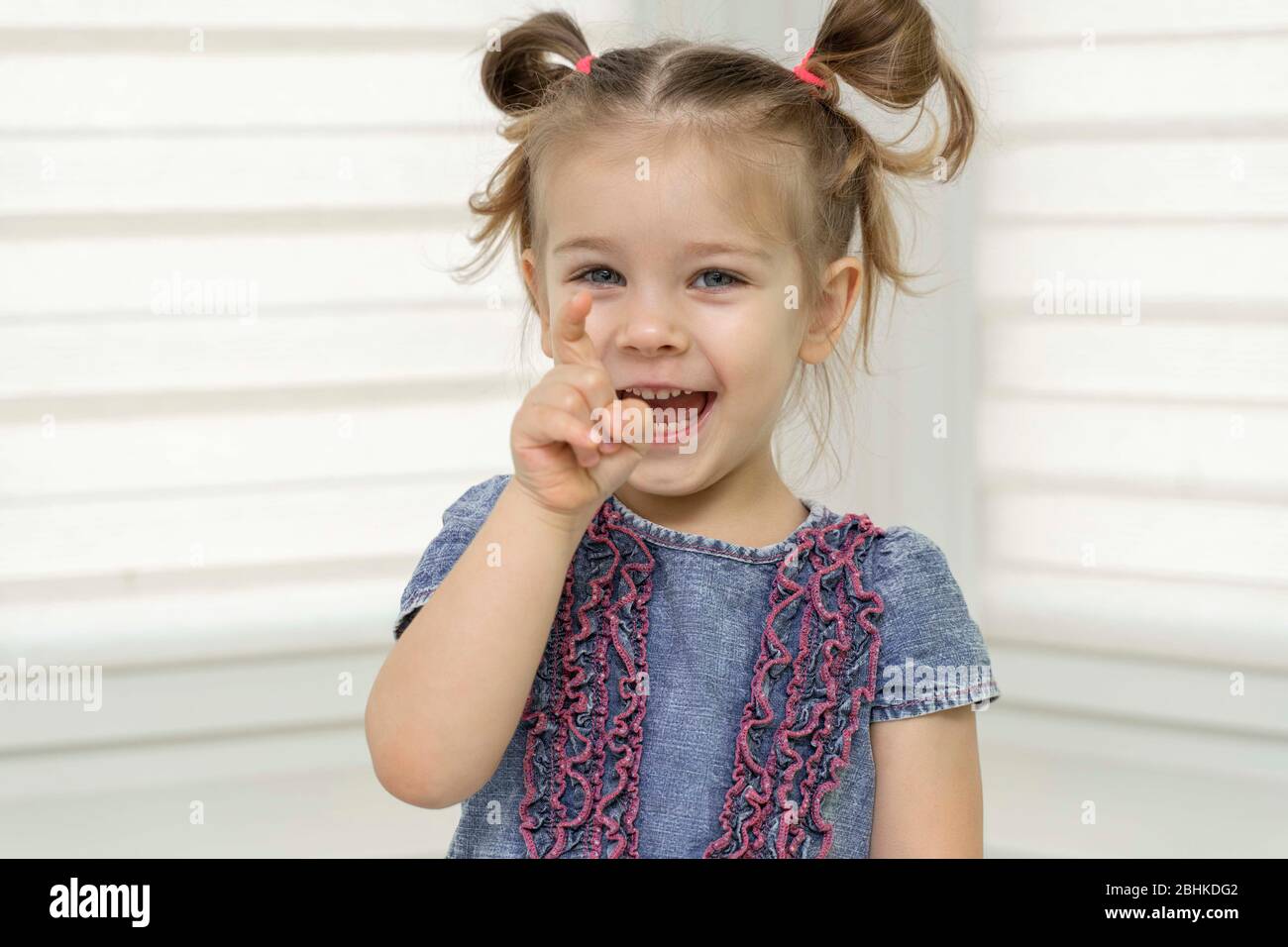 little girl 4 years old in a blue dress, playful face, warning sign ...