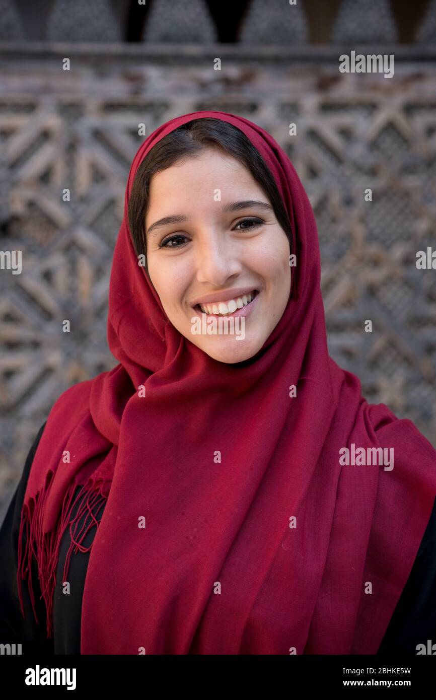 Portrait of young muslim woman smiling in traditional clothing with red ...