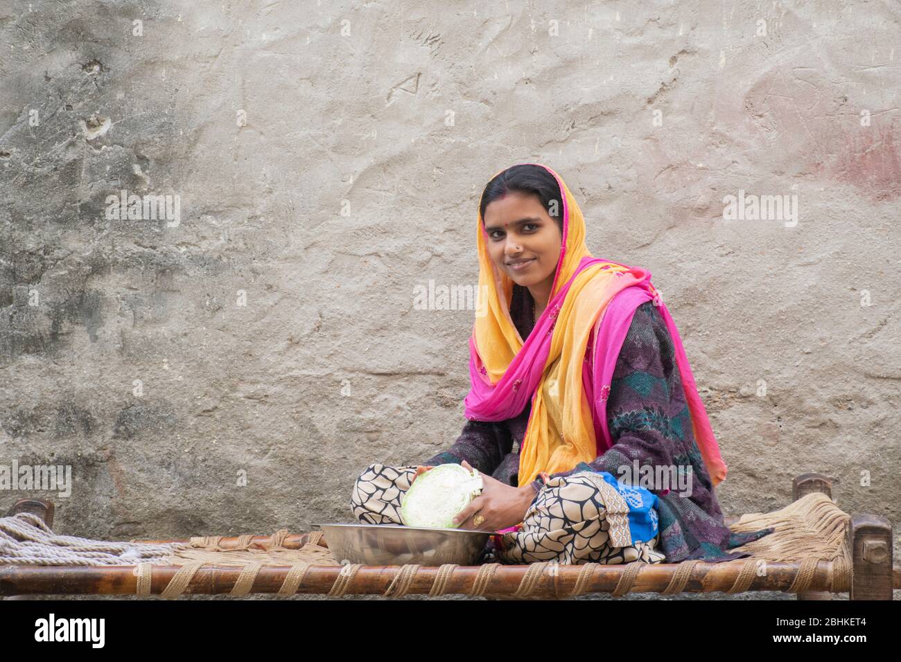 indian Rural villager woman sitting Charpai and Cutting Vegetable Stock ...
