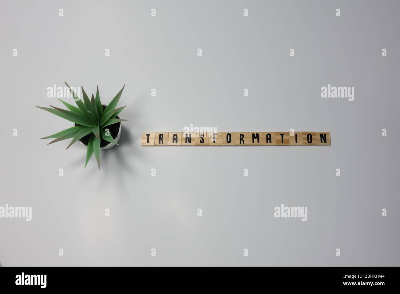 The word Transformation written in wooden letter tiles on a white ...
