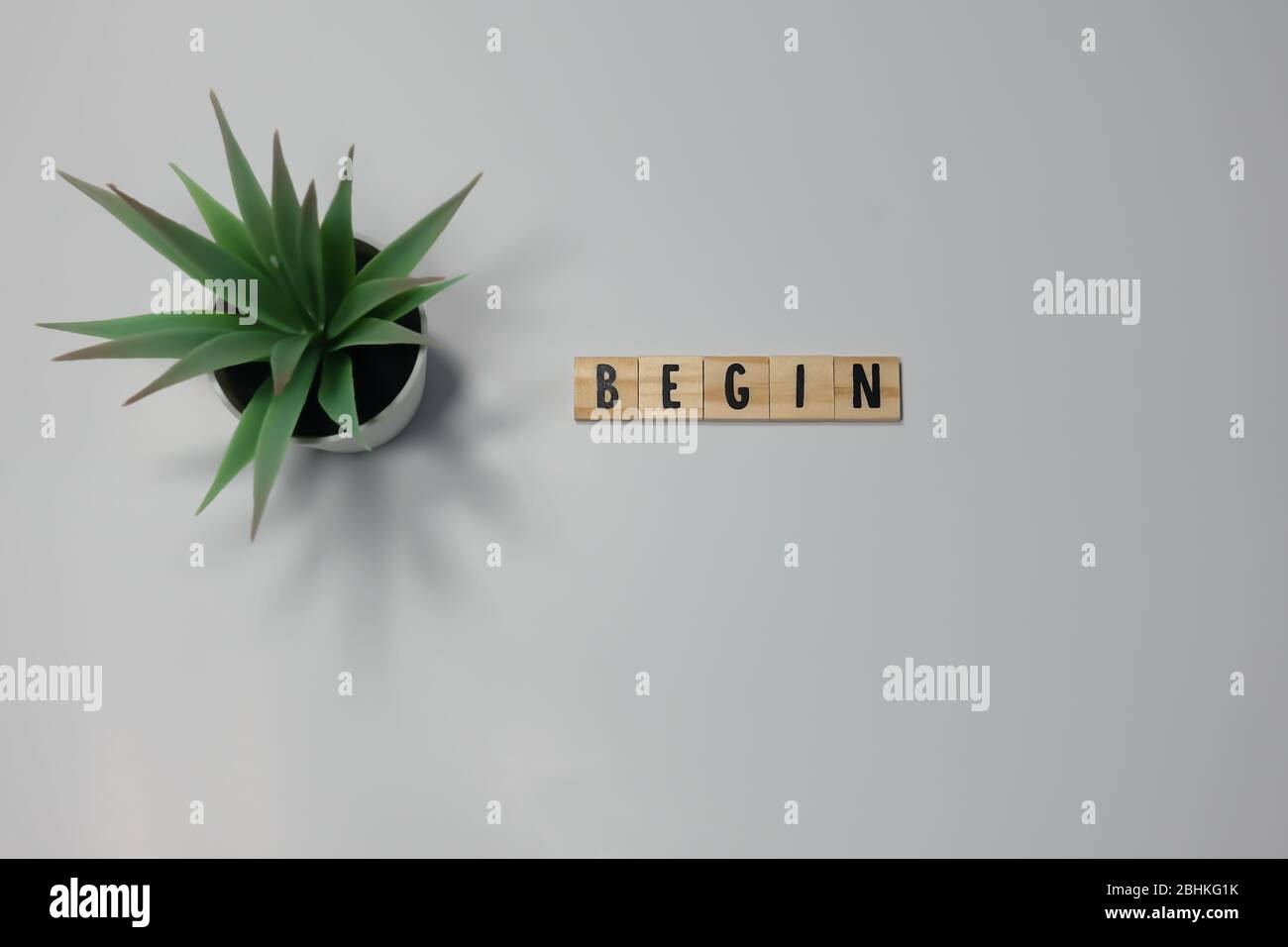 The word Begin written in wooden letter tiles on a white background ...
