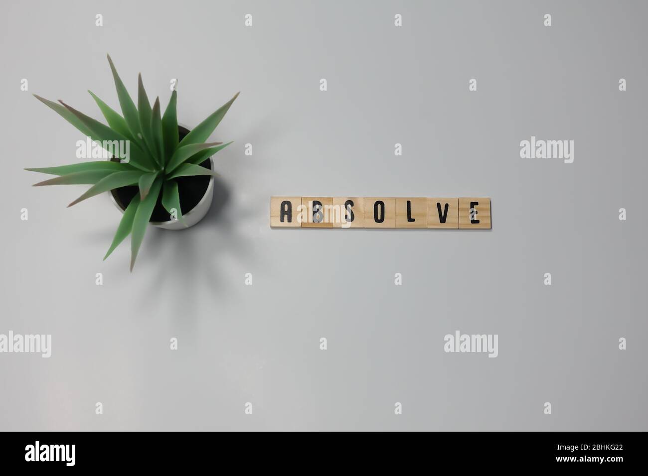 The word Absolve written in wooden letter tiles on a white background ...