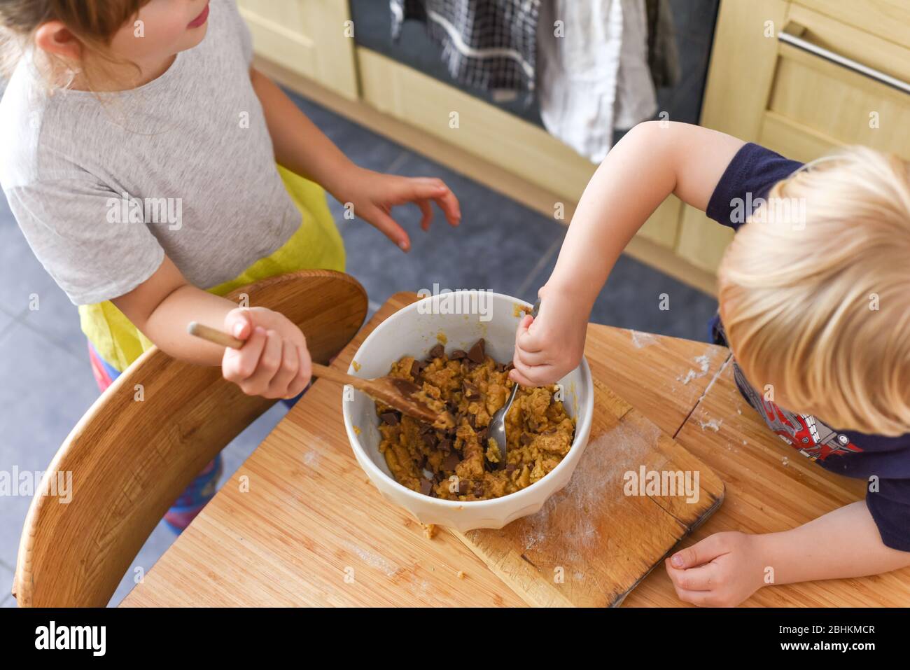 Children stir a mixing bowl in the kitchen at home while baking cookies ...