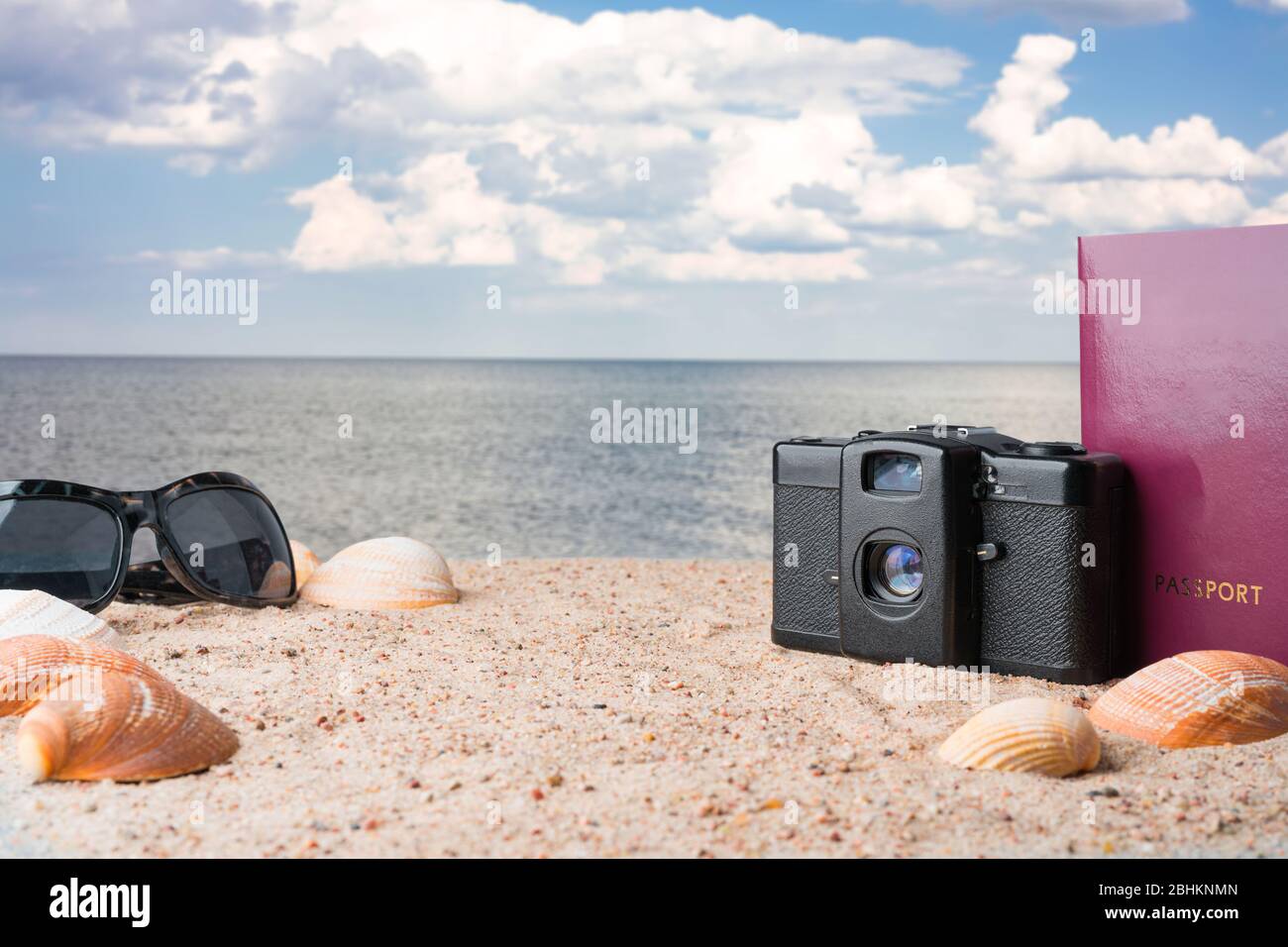 Passport, vintage film camera, sunglasses and seashells on golden beach ...