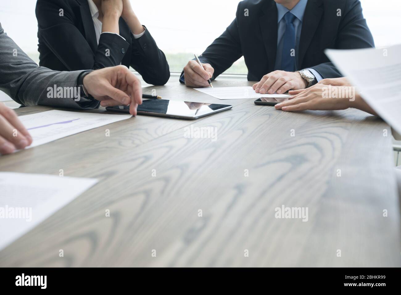Business people sitting around the desk in a meeting and working with ...