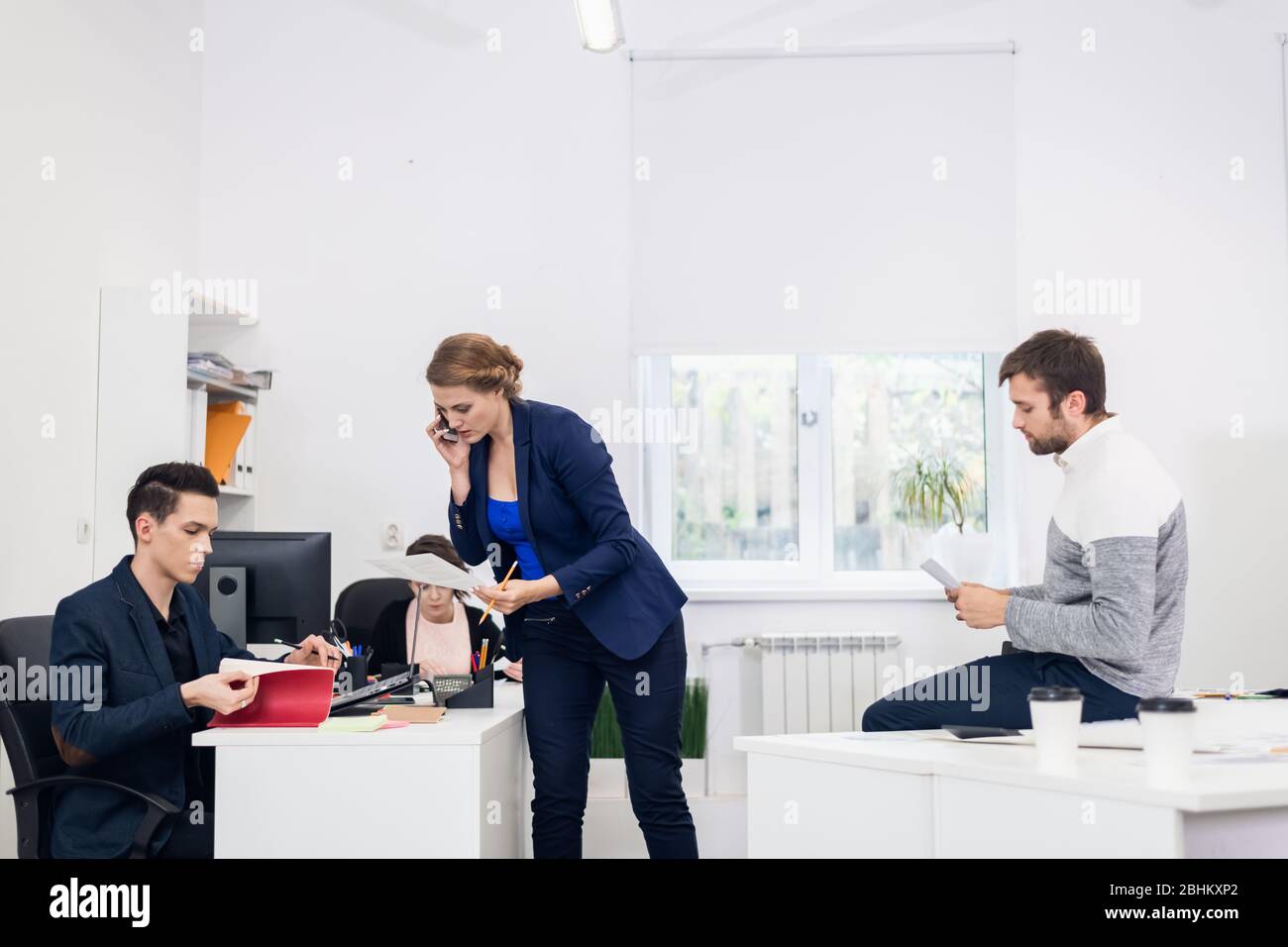 A busy work day in the modern office. Four people working in the office ...