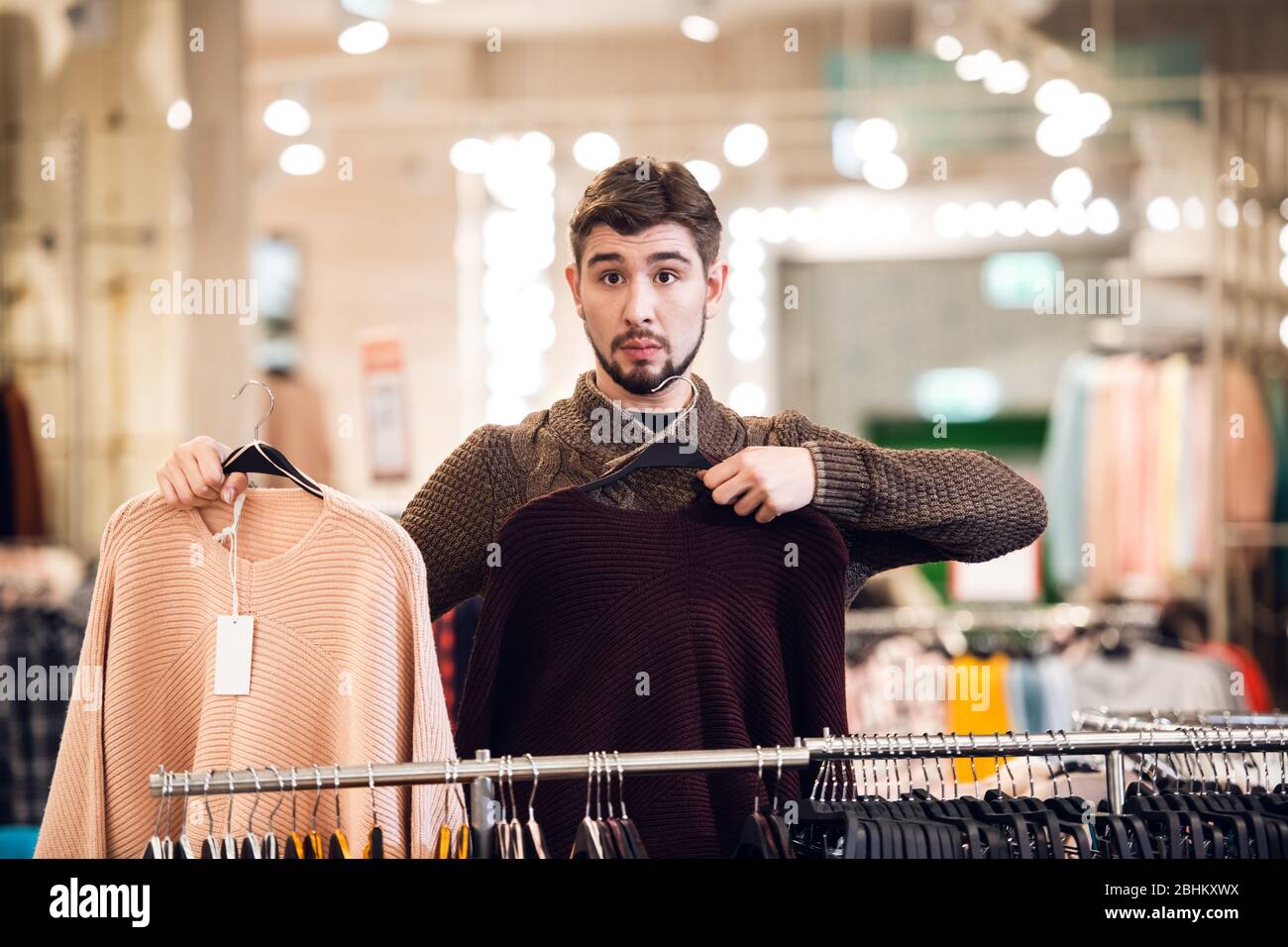 A young man showing his girlfriend the available colors of sweaters in ...