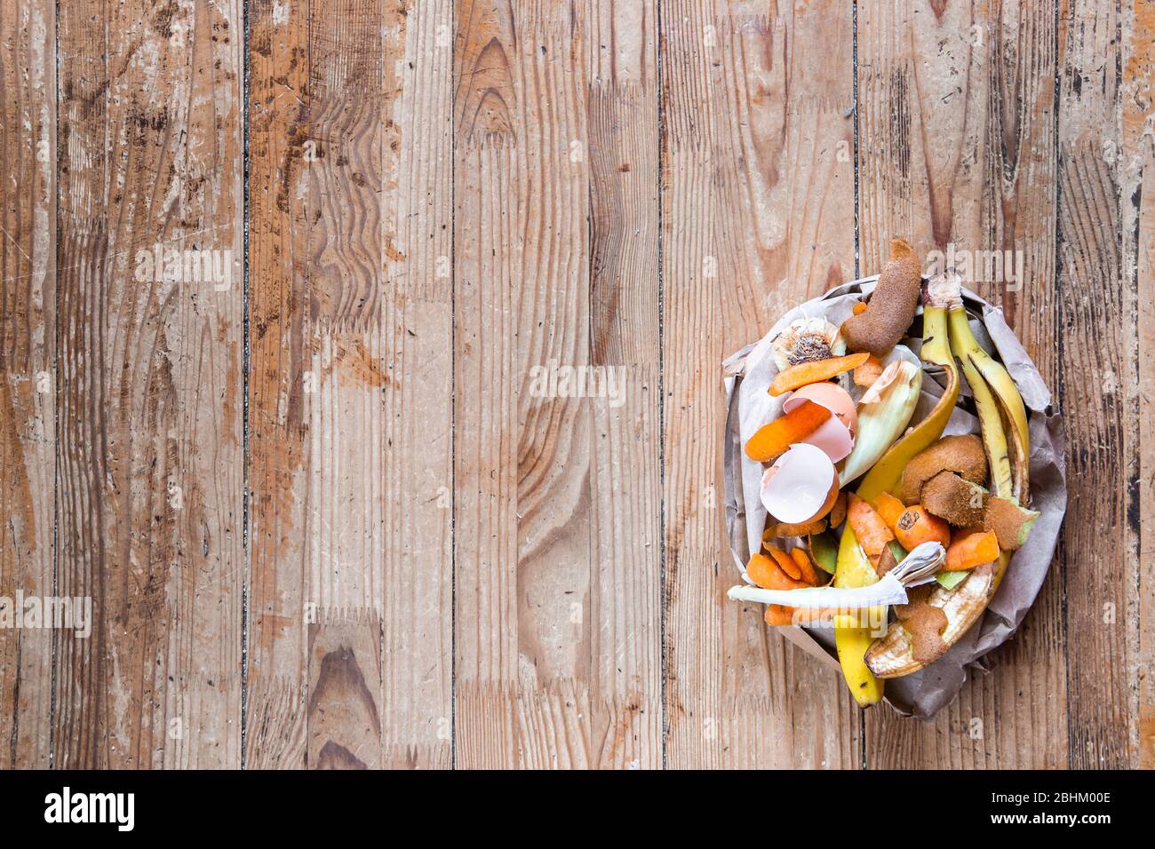Organic waste in a paper bag on a wooden background with space for text ...