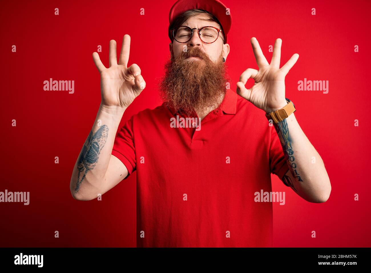 Young handsome delivery man wearing glasses and red cap over isolated ...