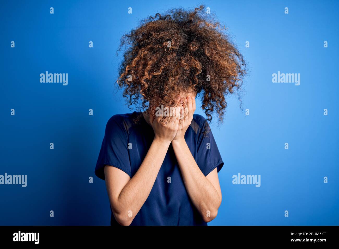 Young beautiful woman with curly hair and piercing wearing casual blue ...