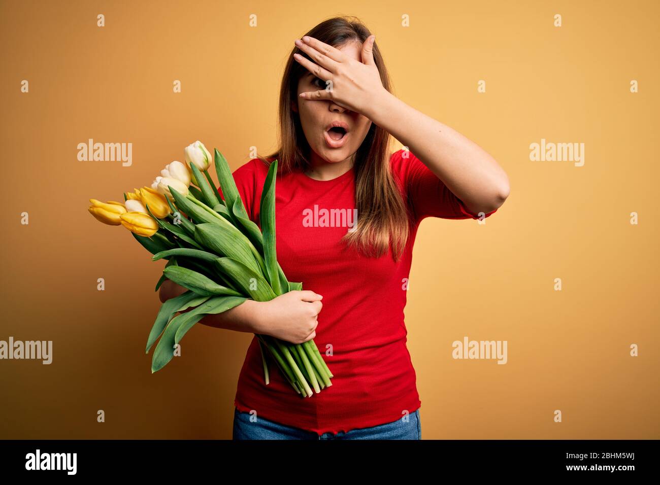 Young blonde woman holding romantic bouquet of tulips flowers over ...