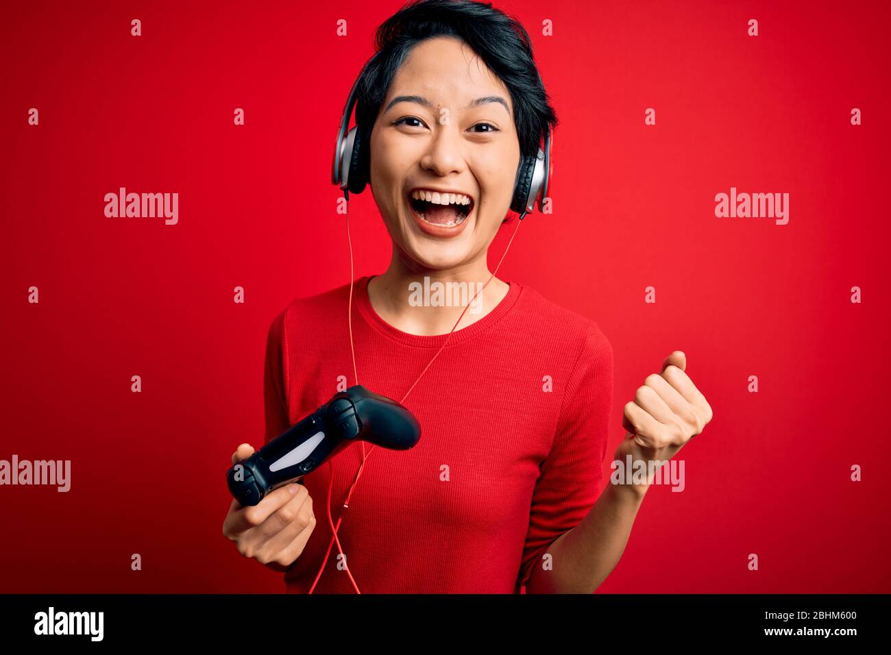 Young beautiful asian gamer girl playing video game using joystick and ...