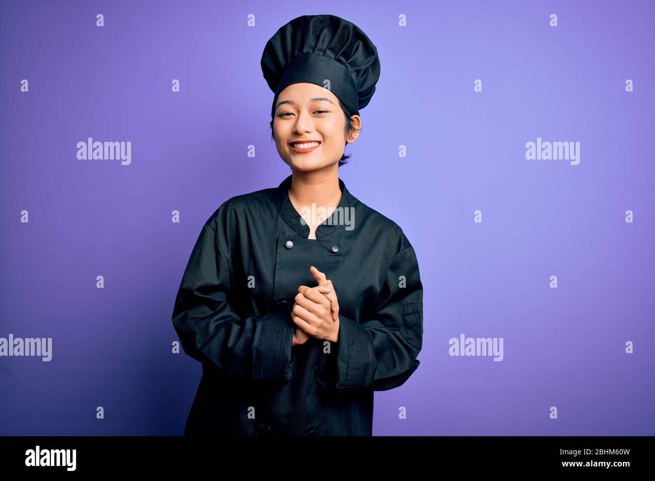 Young beautiful chinese chef woman wearing cooker uniform and hat over ...