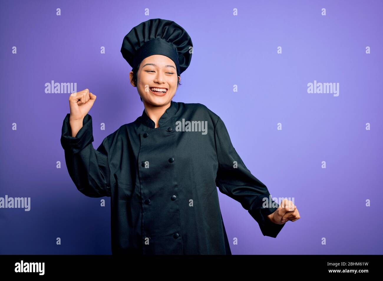 Young beautiful chinese chef woman wearing cooker uniform and hat over ...