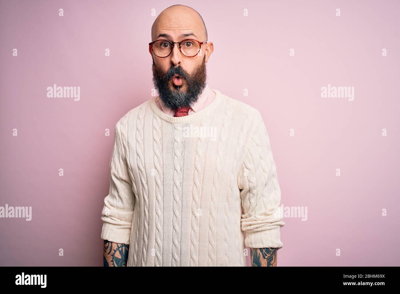 Handsome bald man with beard and tattoo wearing glasses and sweater ...