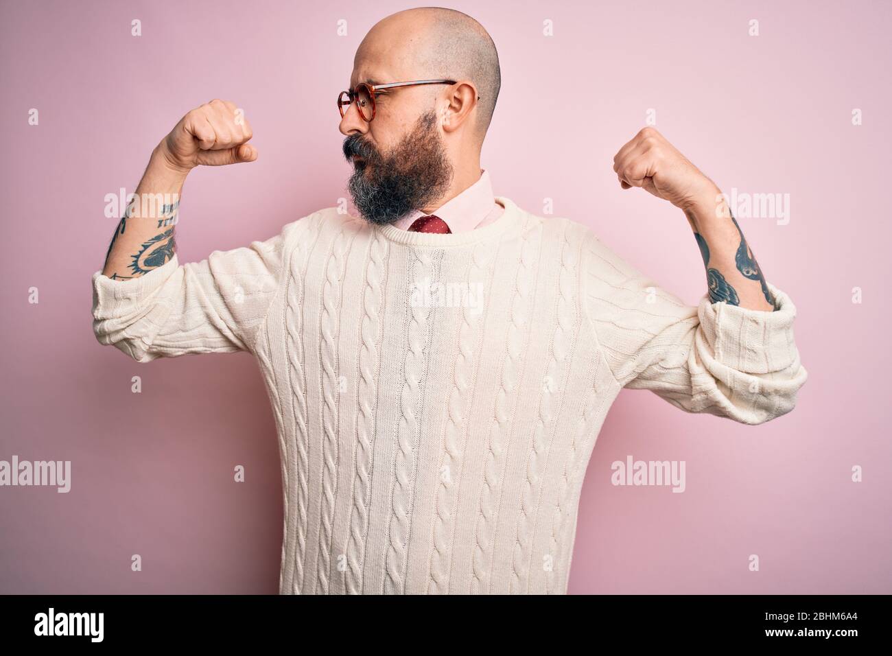 Handsome bald man with beard and tattoo wearing glasses and sweater ...