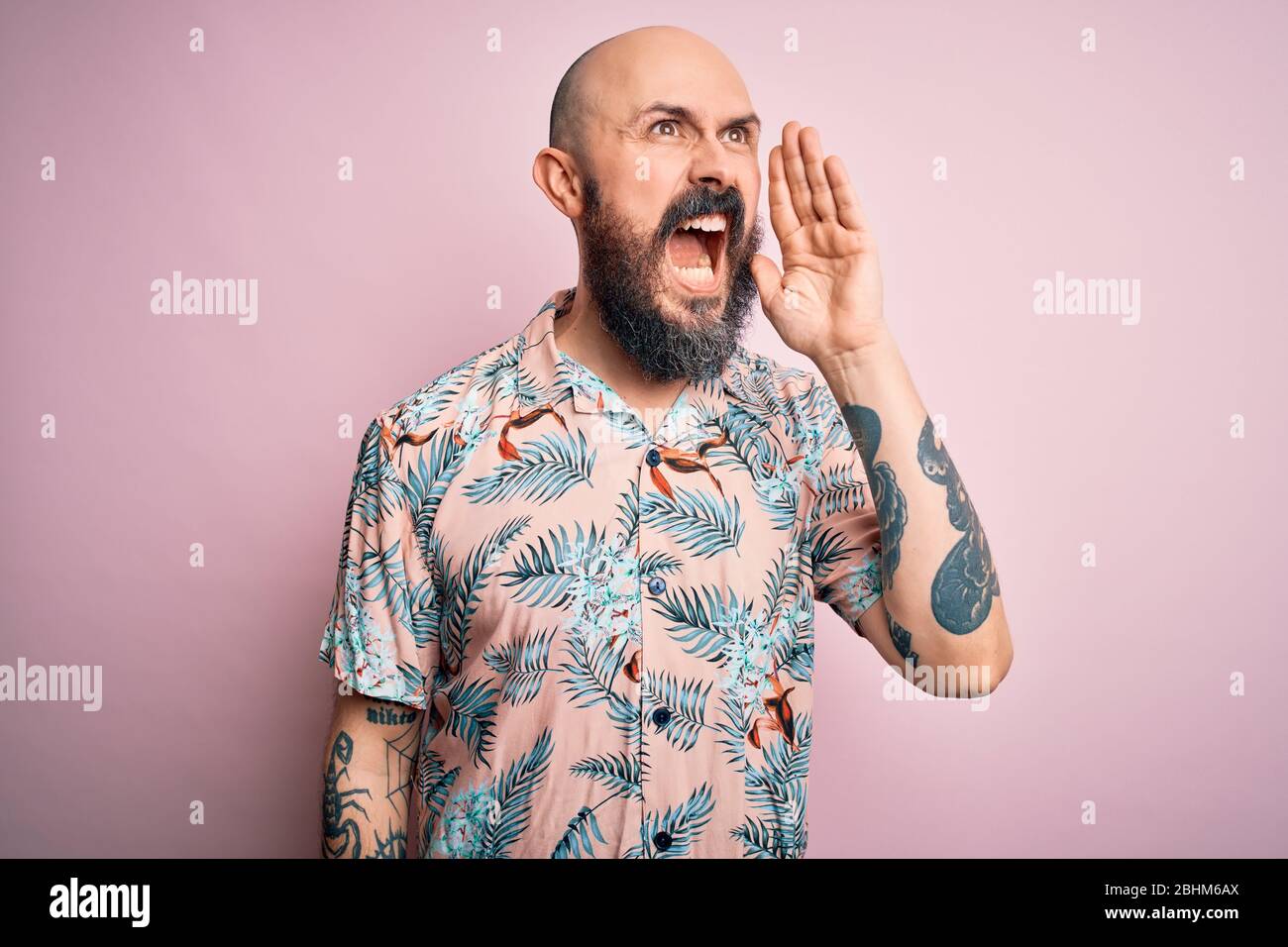Handsome bald man with beard and tattoo wearing casual floral shirt ...