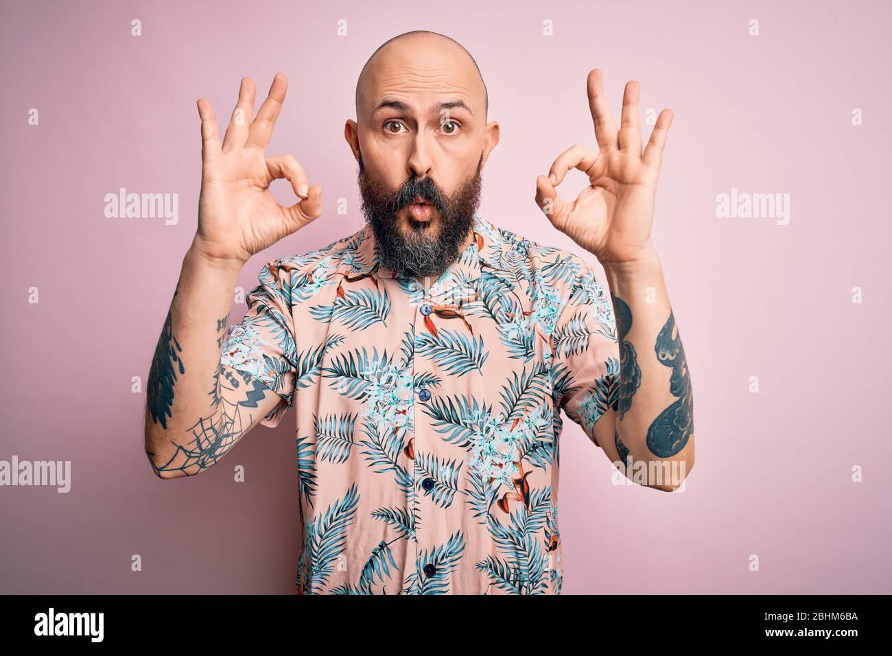 Handsome bald man with beard and tattoo wearing casual floral shirt ...