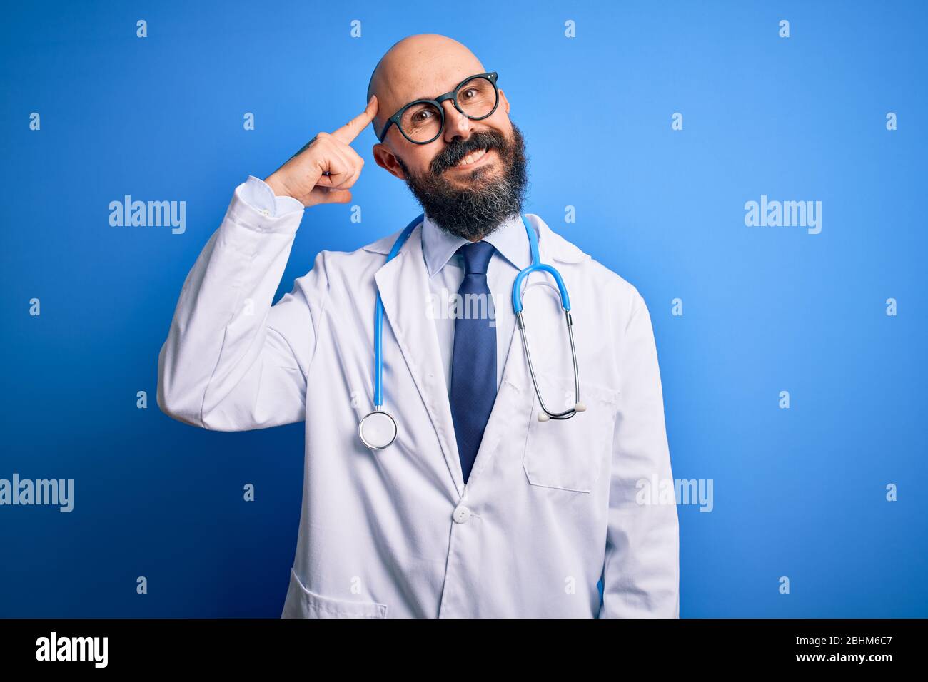 Handsome bald doctor man with beard wearing glasses and stethoscope ...