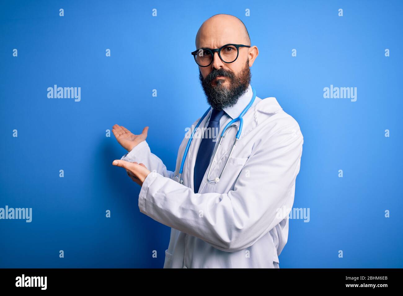 Handsome bald doctor man with beard wearing glasses and stethoscope ...