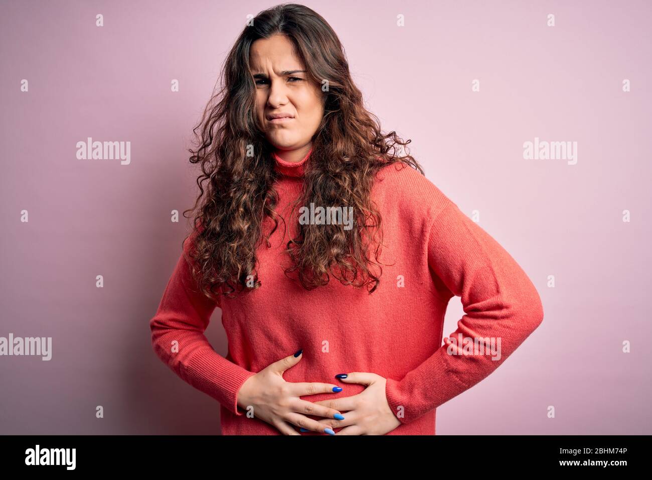 Young beautiful woman with curly hair wearing turtleneck sweater over ...