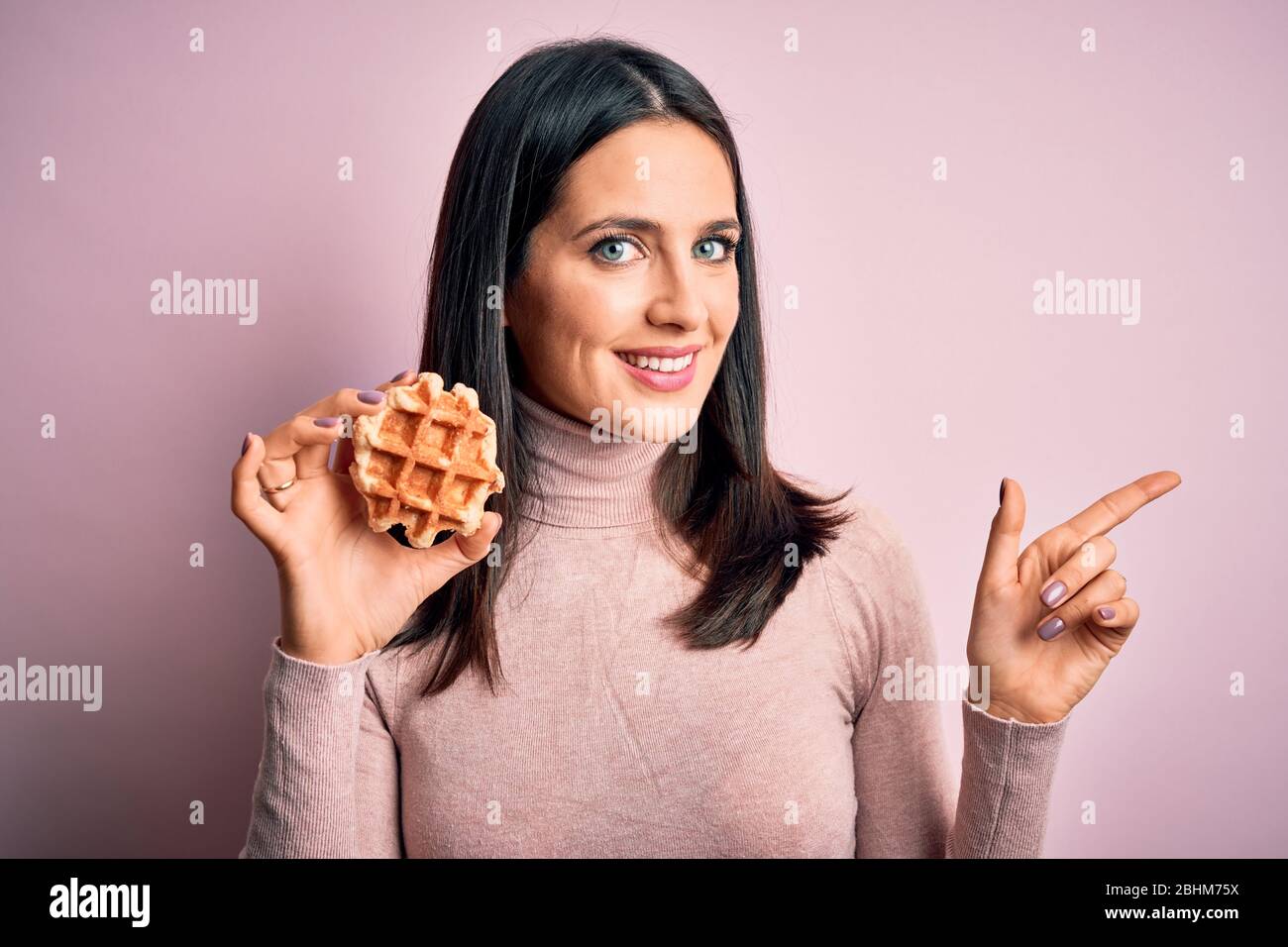Young brunette woman with blue eyes eating sweet waffle for breakfast ...