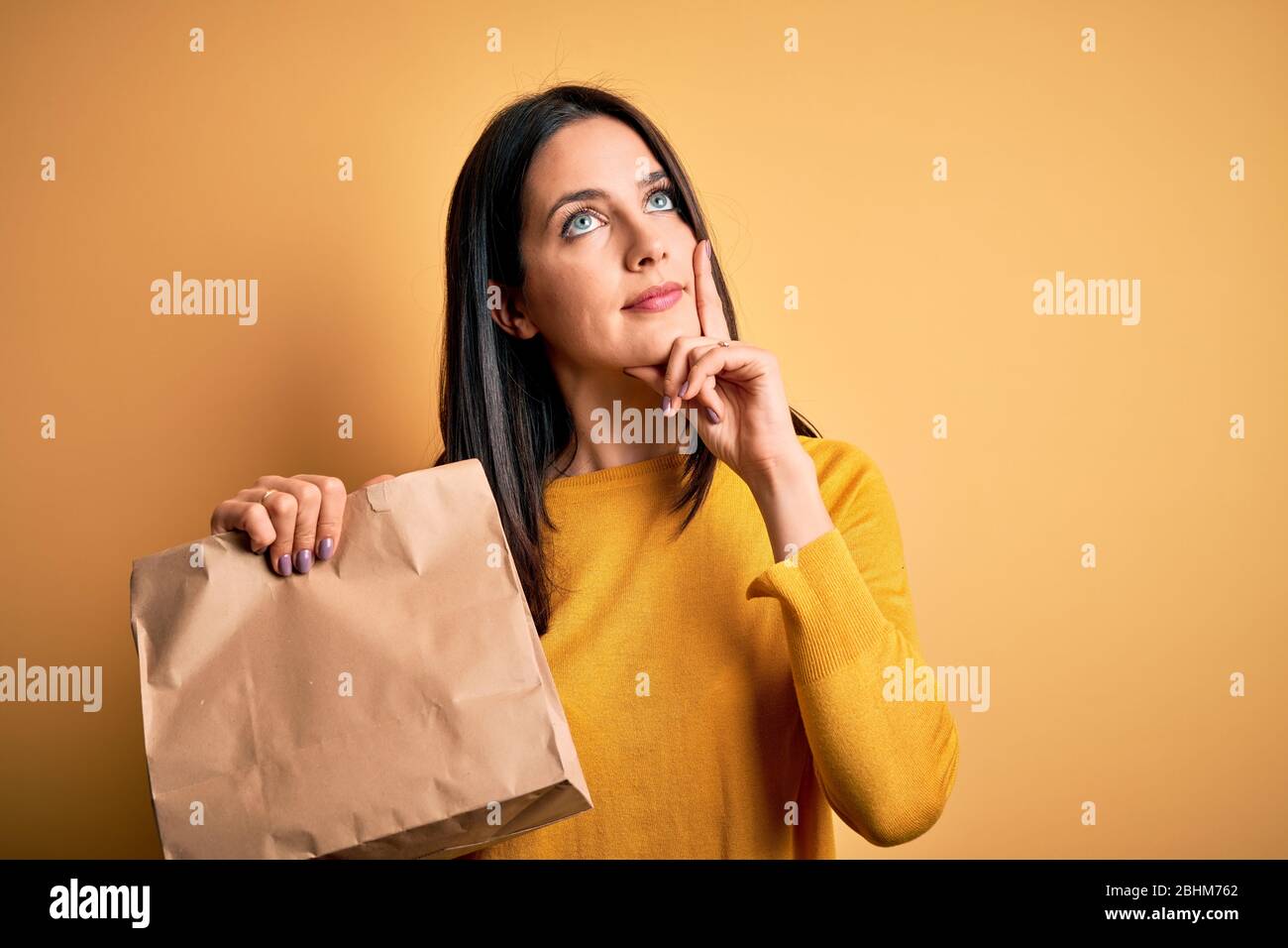 Young brunette woman with blue eyes holding delivery paper bag with ...