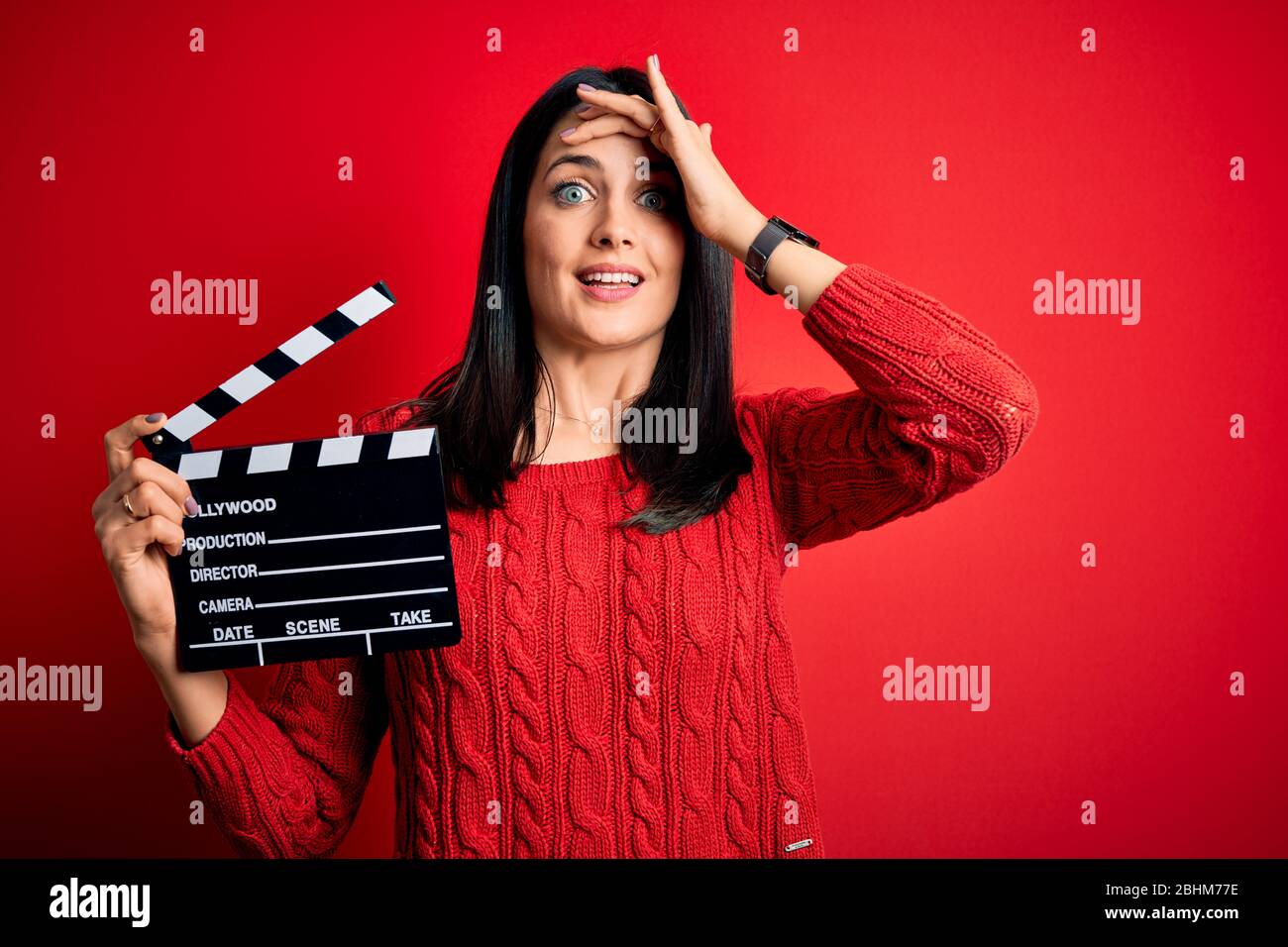 Young director woman with blue eyes making movie holding clapboard over ...