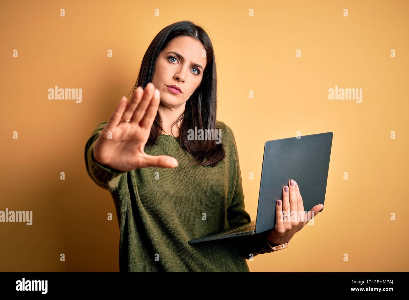 Young brunette woman with blue eyes working using computer laptop over ...