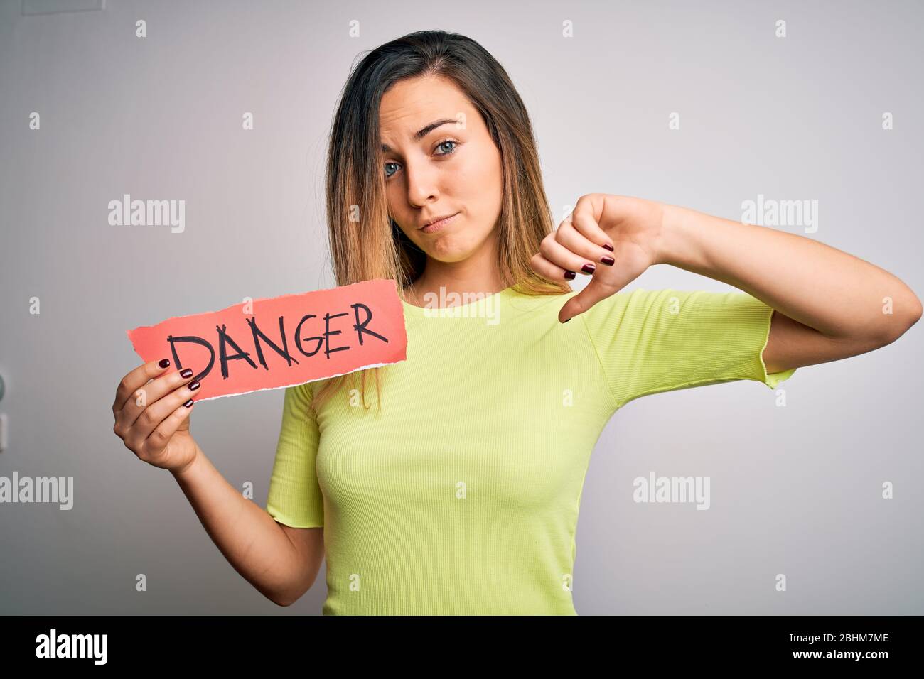 Young beautiful blonde woman with blue eyes holding paper with danger ...