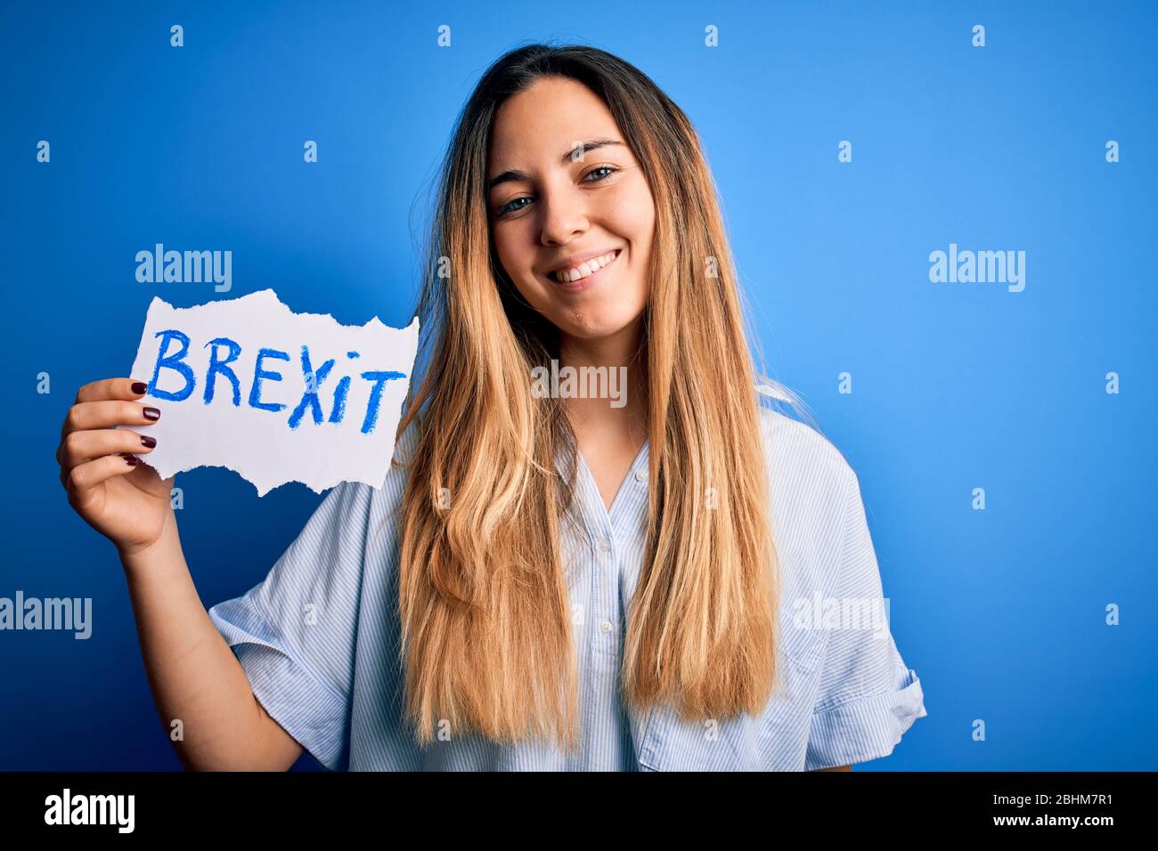 Young beautiful blonde woman with blue eyes holding banner with brexit ...