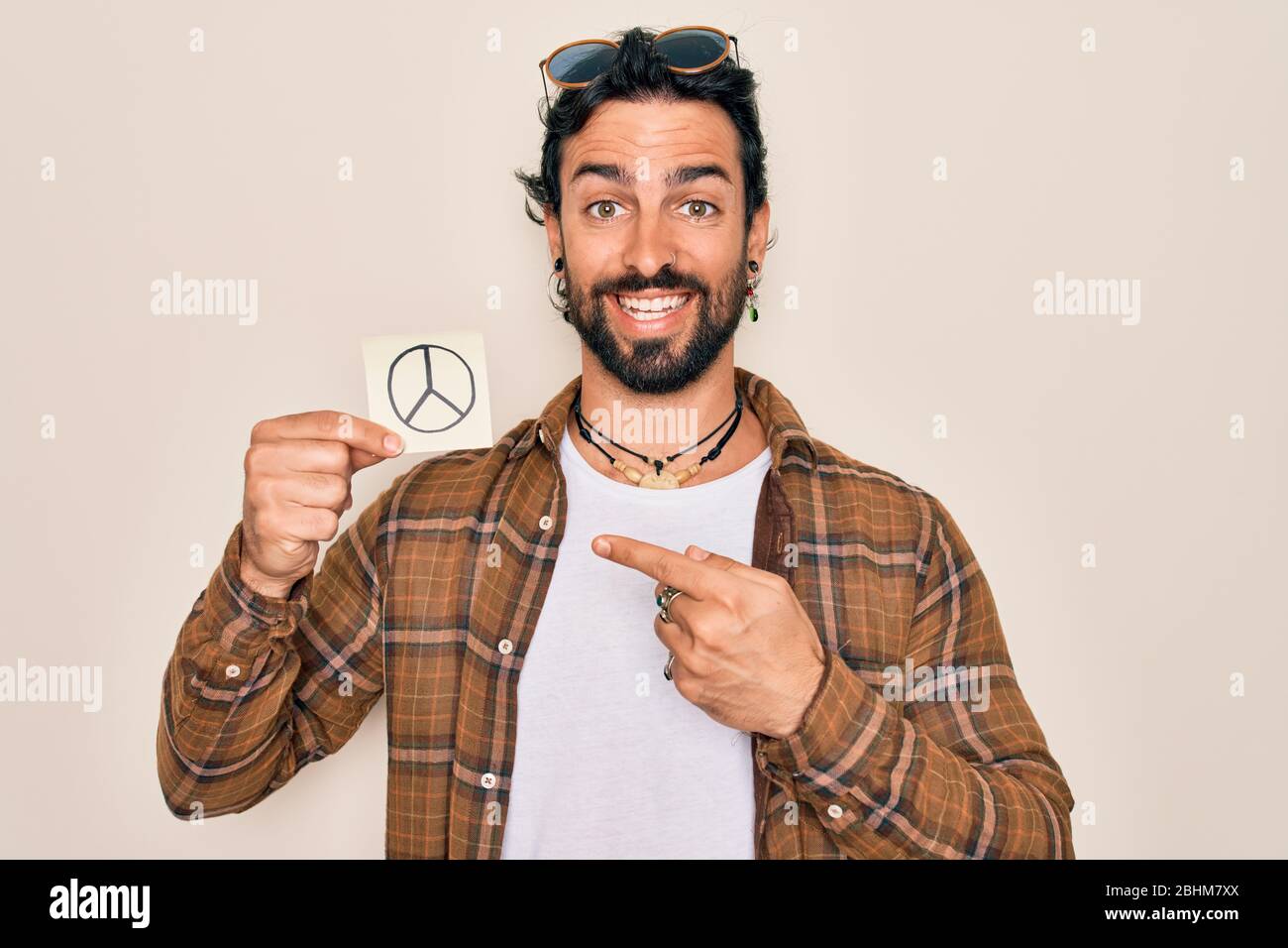 Young handsome hispanic bohemian hipster man with bear holding paper ...