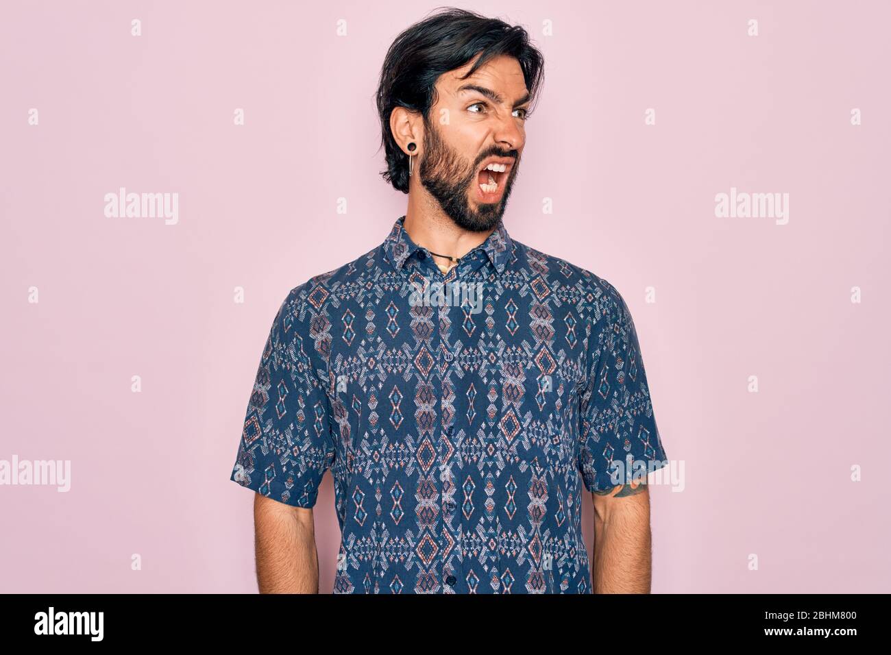 Young handsome hispanic bohemian man wearing hippie style over pink ...