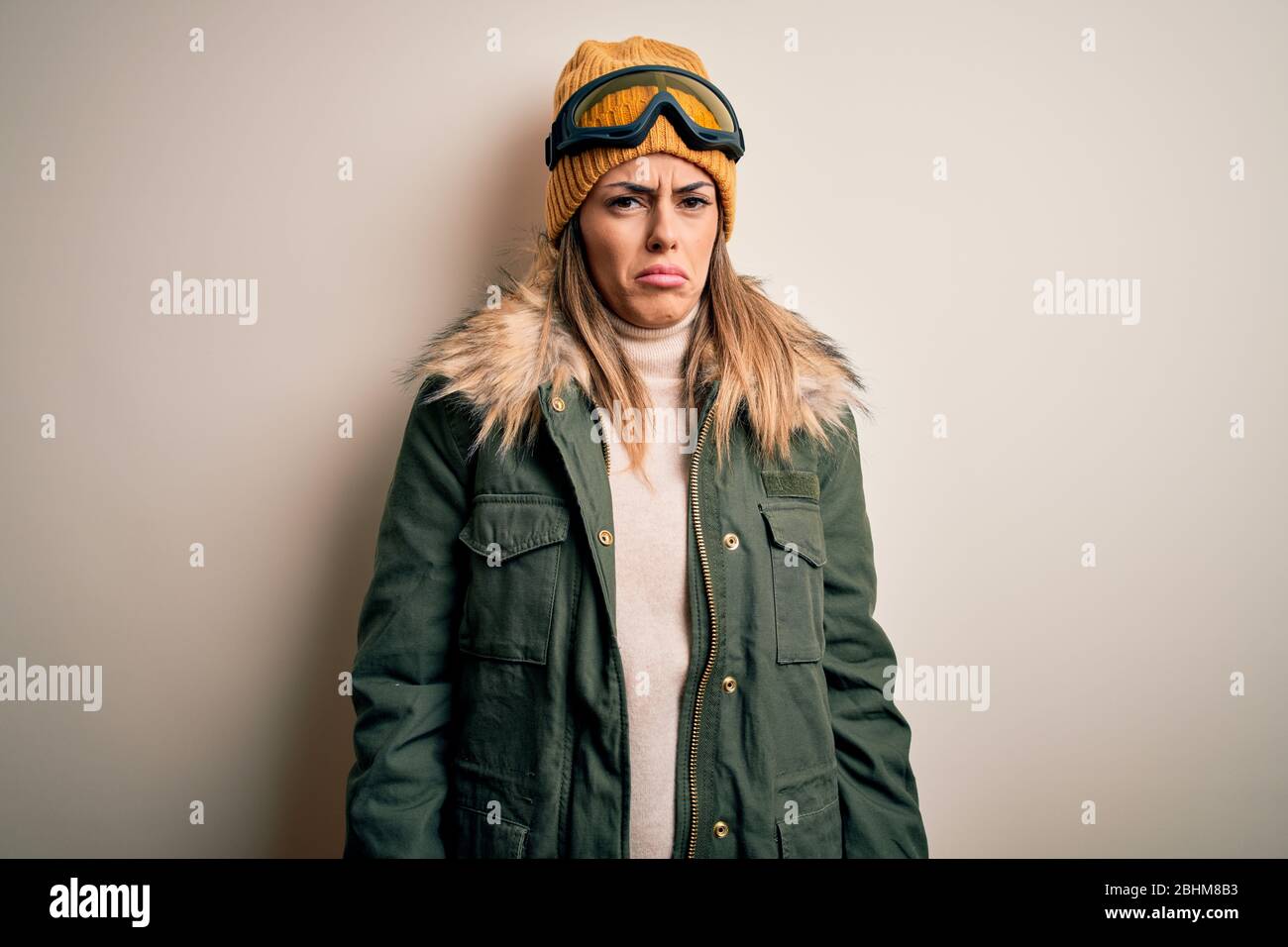 Young brunette skier woman wearing snow clothes and ski goggles over ...