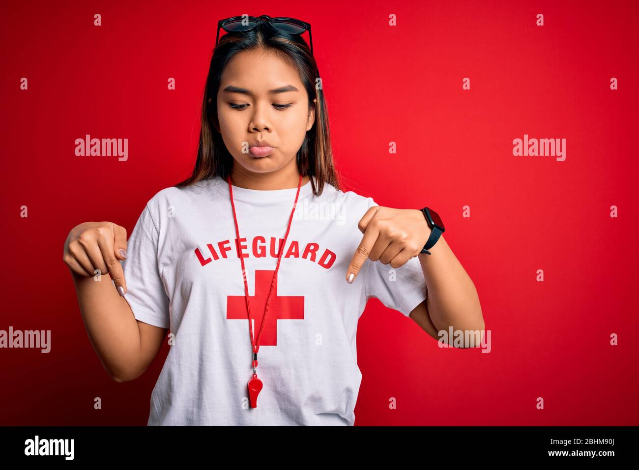 Young asian lifeguard girl wearing t-shirt with red cross using whistle ...