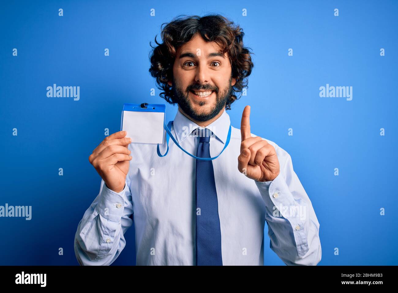 Young handsome business man with beard holding id card identification ...