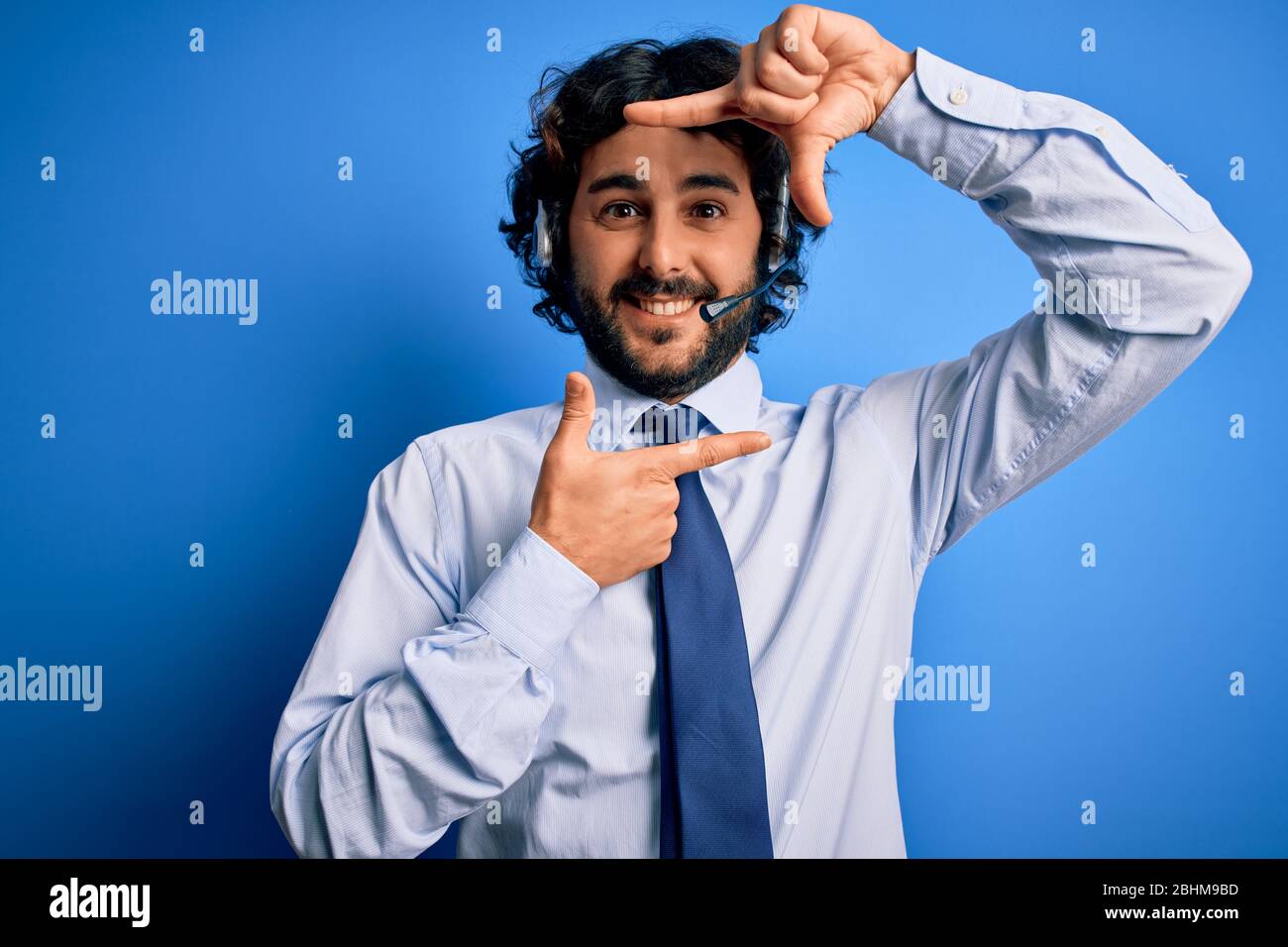 Young handsome call center agent man with beard working using headset ...