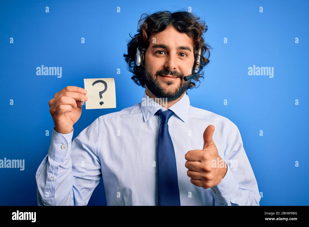 Young call center agent man with beard working using headset holding ...
