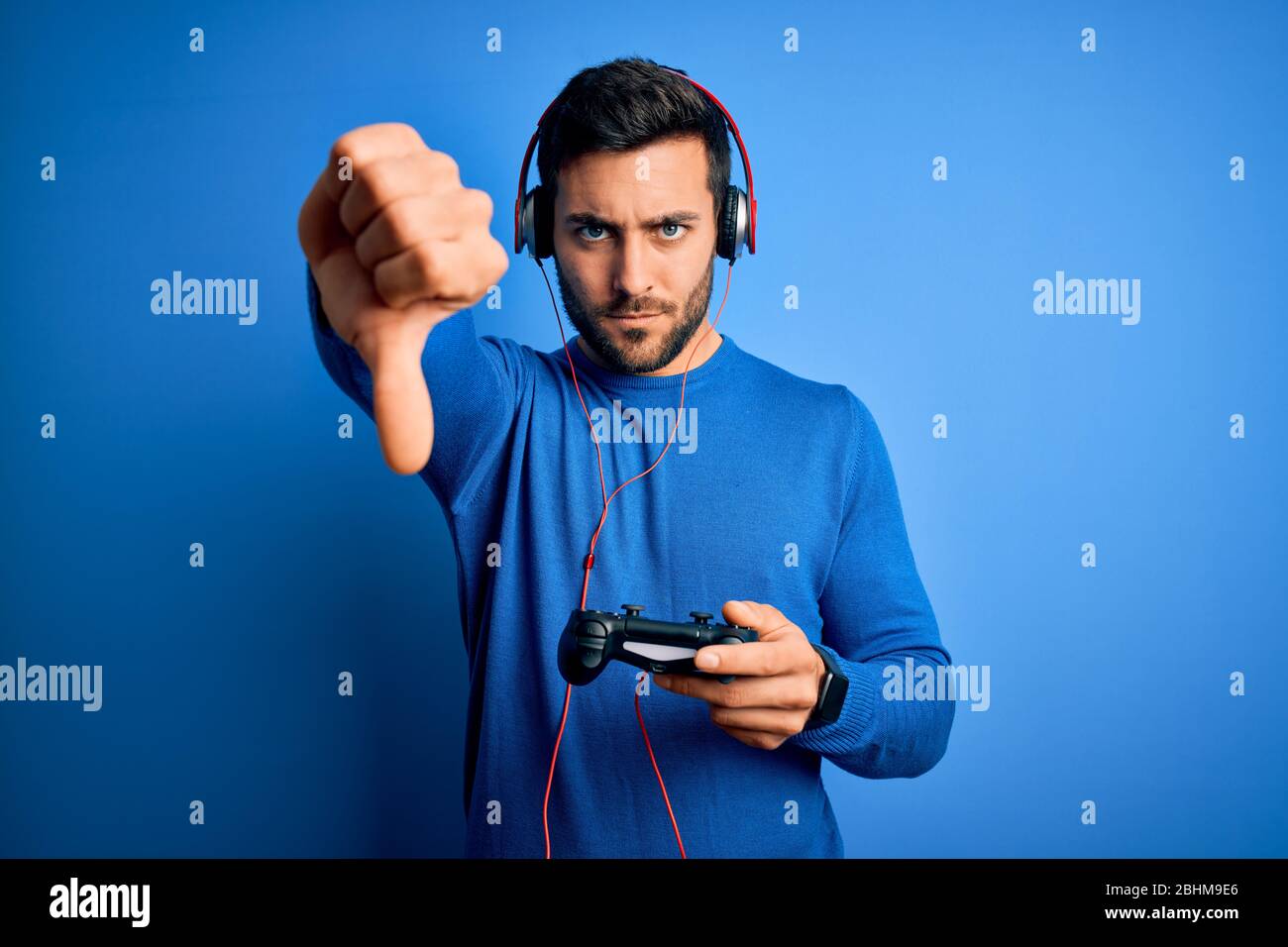 Young handsome gamer man with beard playing video game using joystick ...