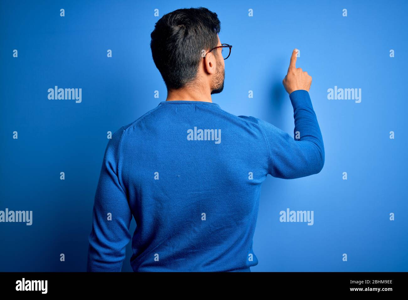 Young handsome man with beard wearing casual sweater and glasses over ...