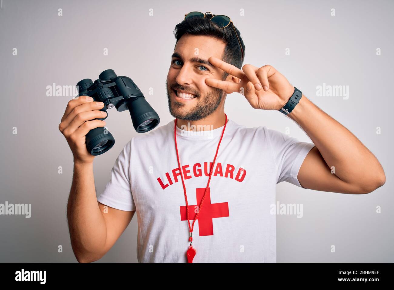 Young lifeguard man with beard wearing t-shirt with red cross and ...