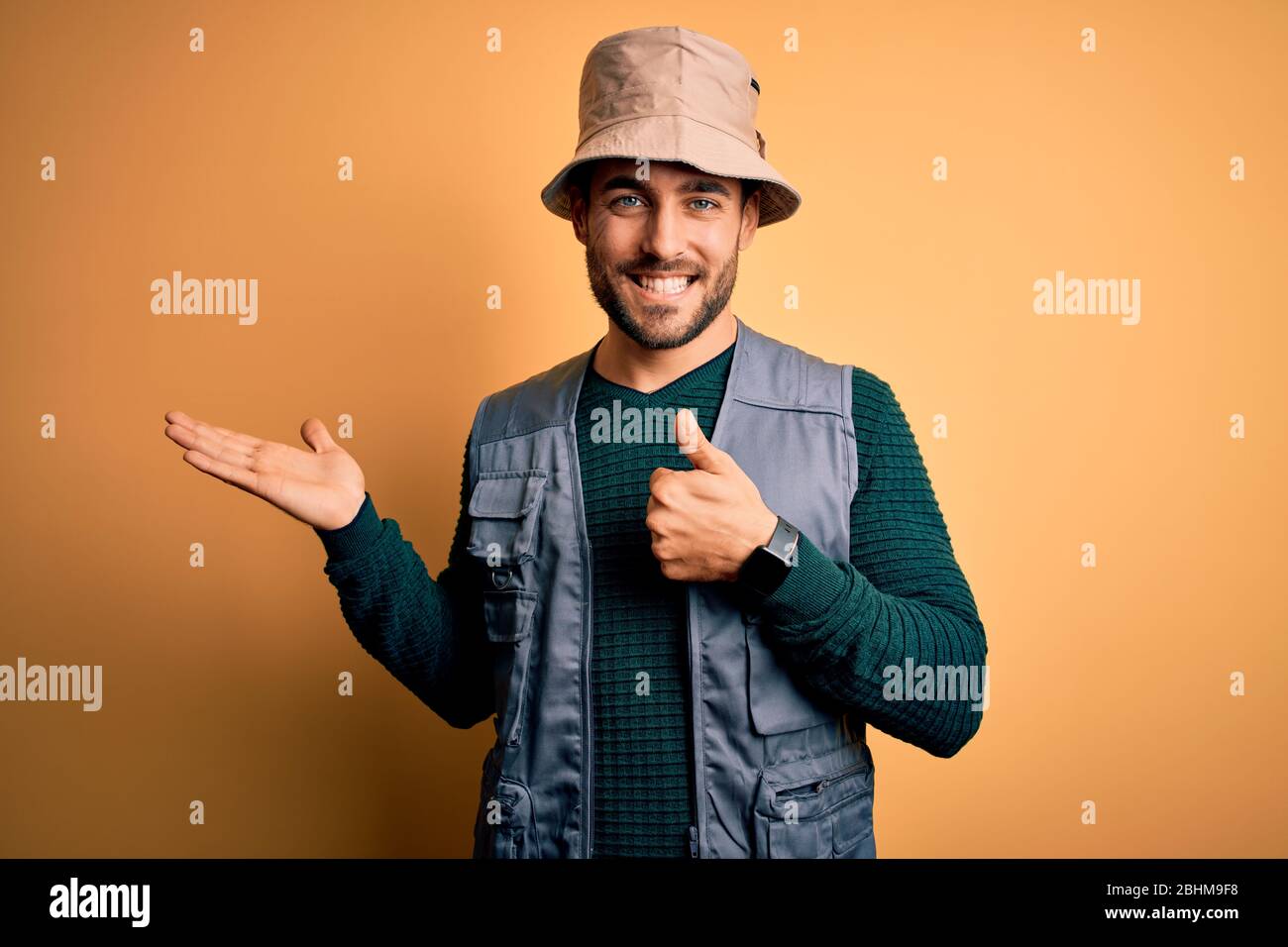 Handsome tourist man with beard on vacation wearing explorer hat over ...