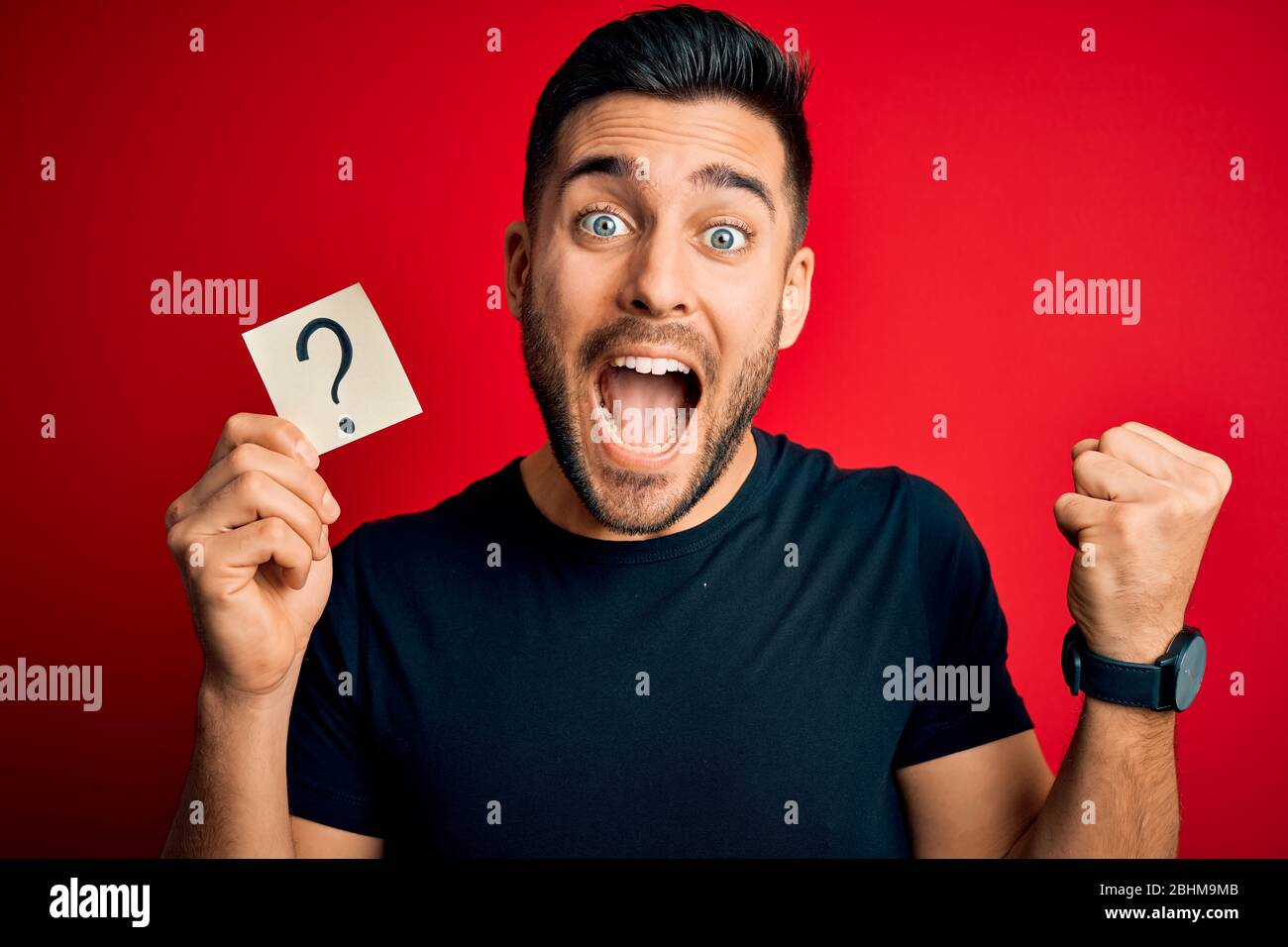 Young handsome man holding paper with question mark symbol over red ...