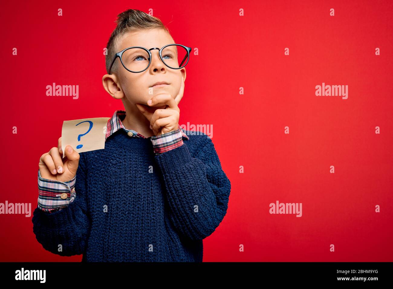 Young little caucasian kid wearing glasses holding paper note with ...